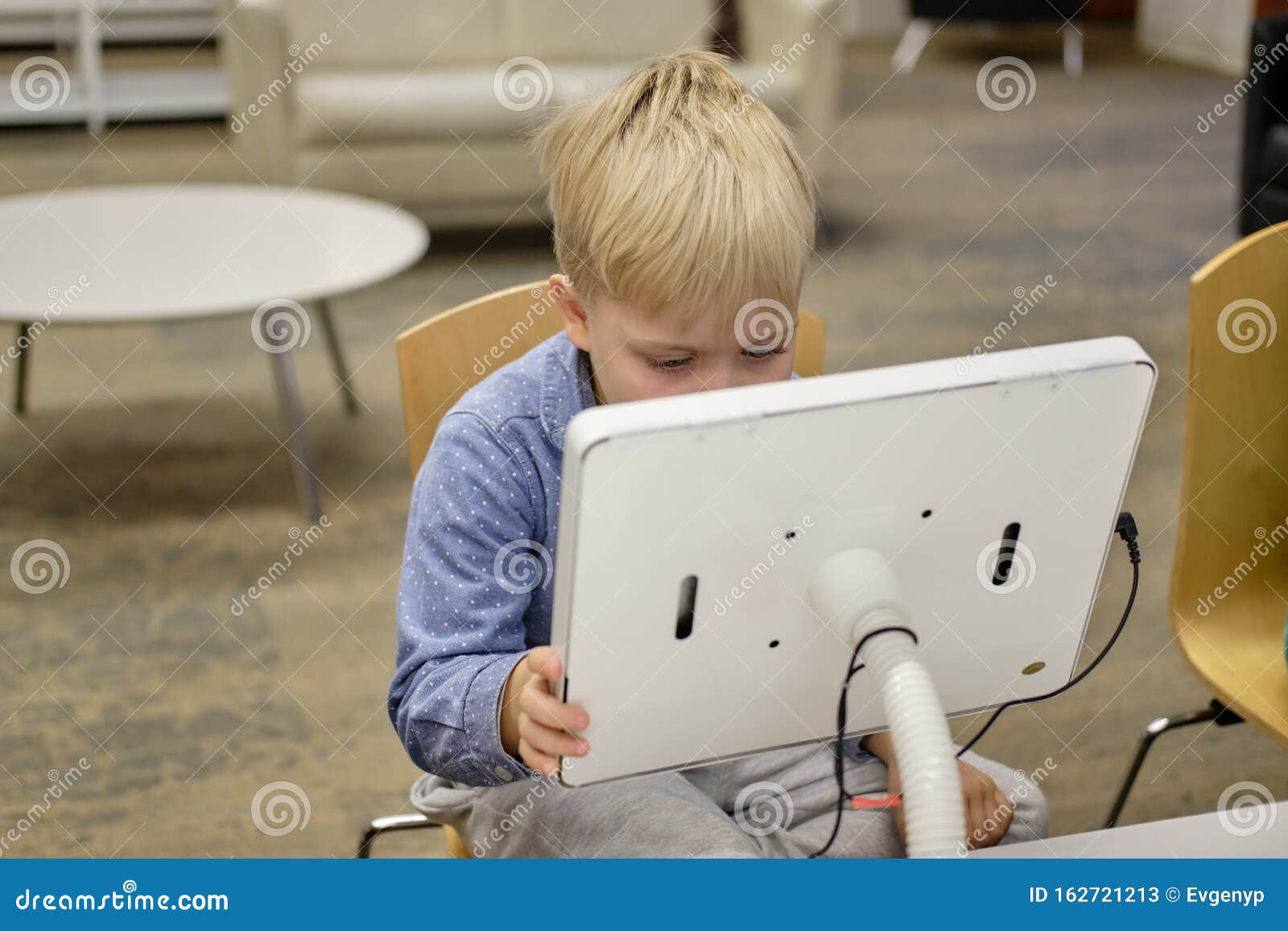 Elementary School Boy Sitting in Library, Using Touchscreen Computer ...