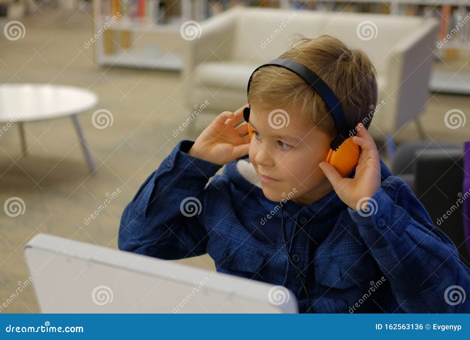 Elementary School Boy Sitting in Library, Using Touchscreen Computer ...