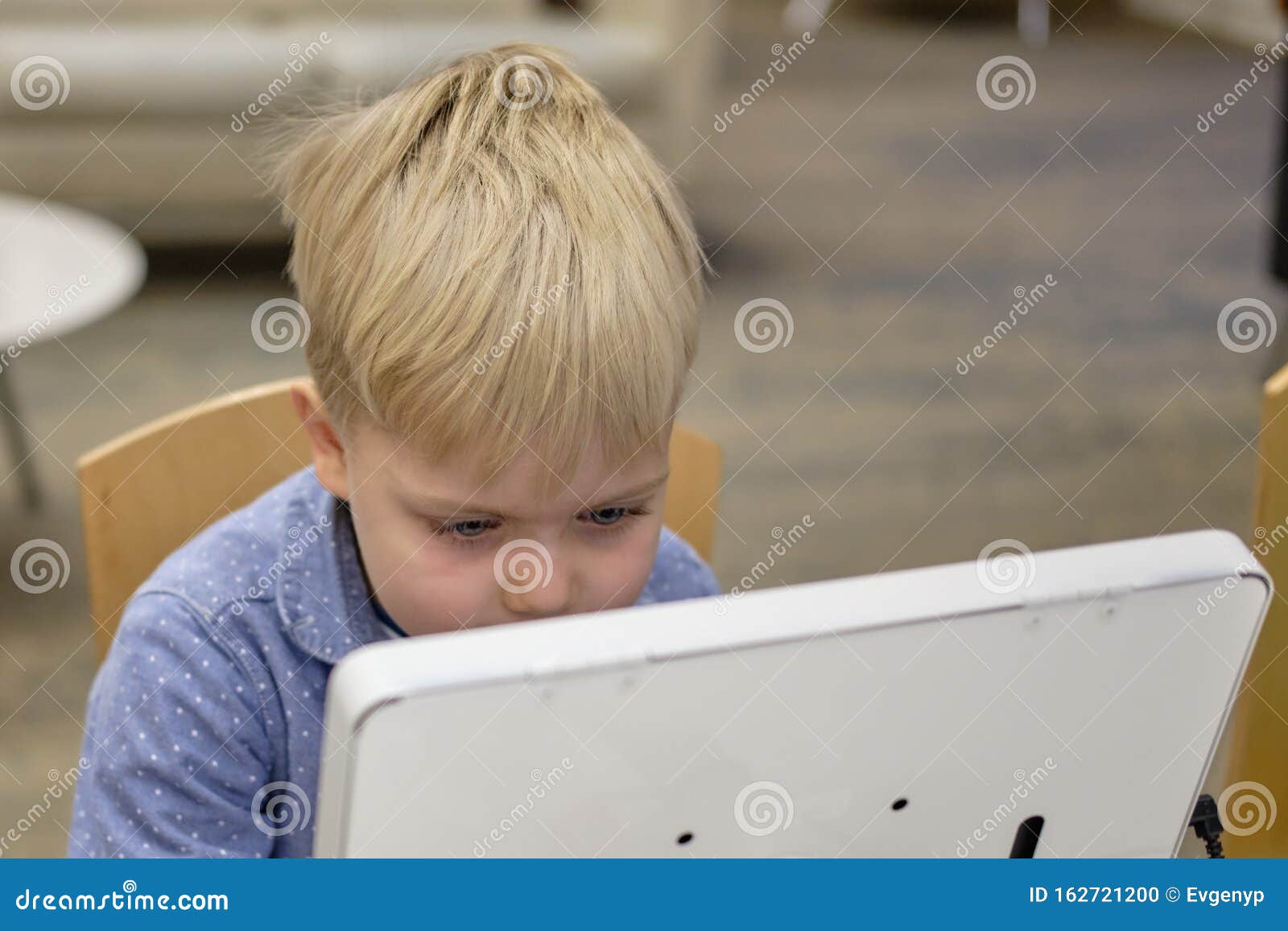 Elementary School Boy Sitting in Library, Using Touchscreen Computer ...