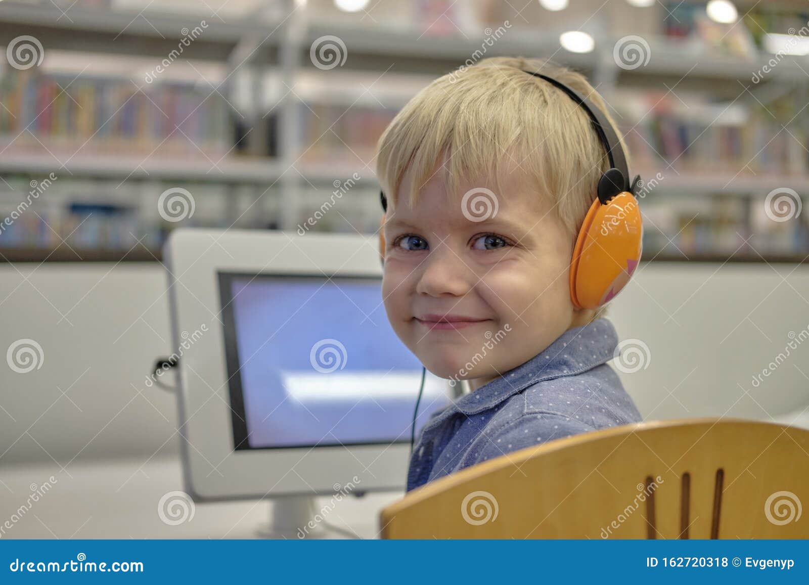 Elementary School Boy Sitting in Library, Using Touchscreen Computer ...