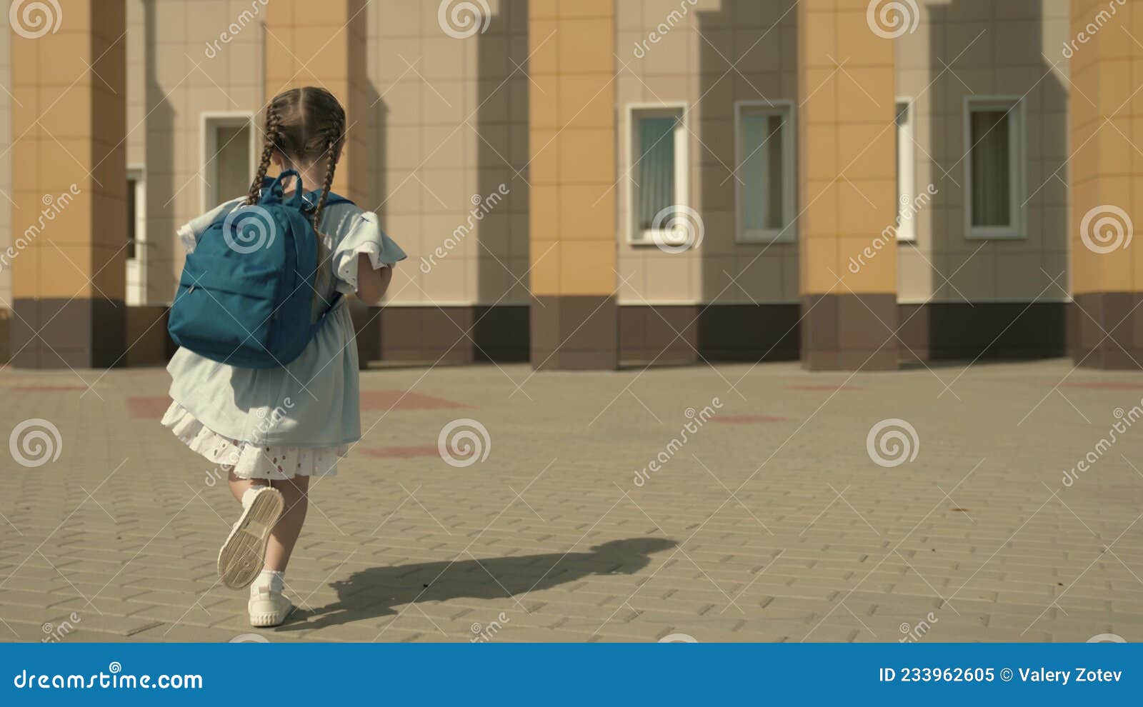 Elementary School Child is Running Around the School Yard with Backpack ...