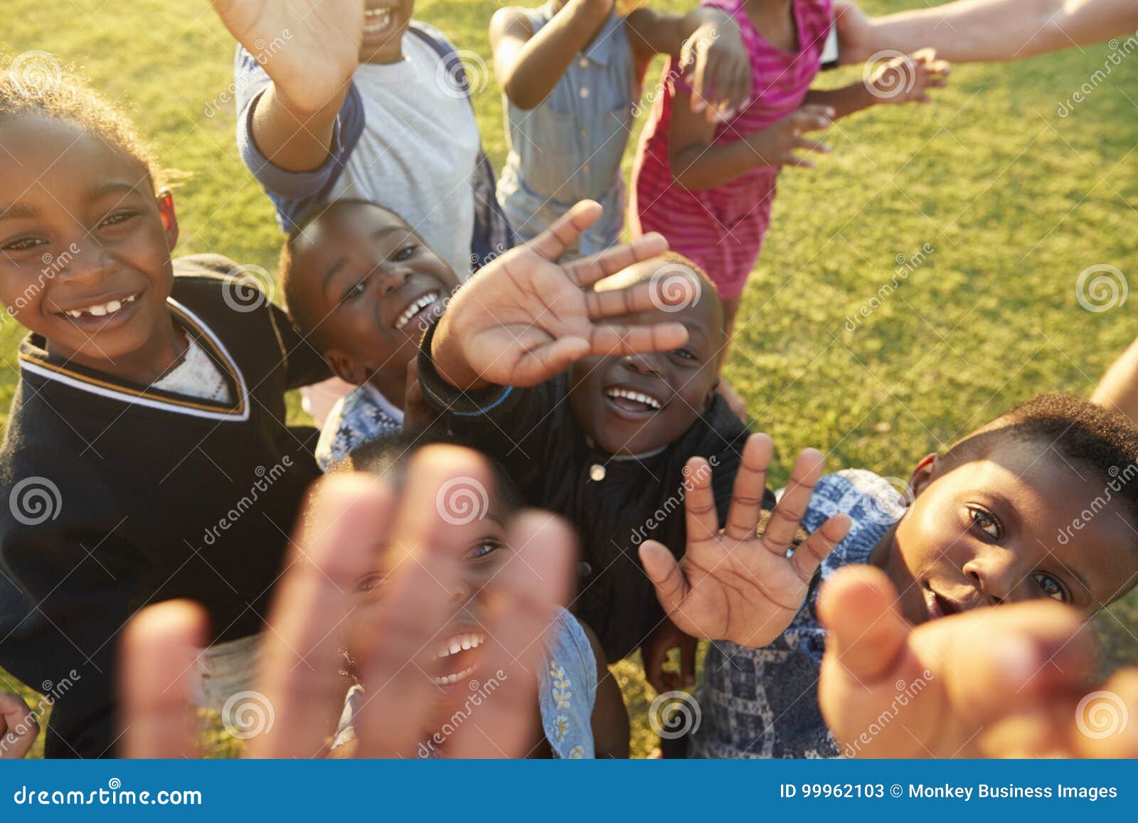 Elementary School Kids in a Field Look Up at Camera Waving Stock Image ...