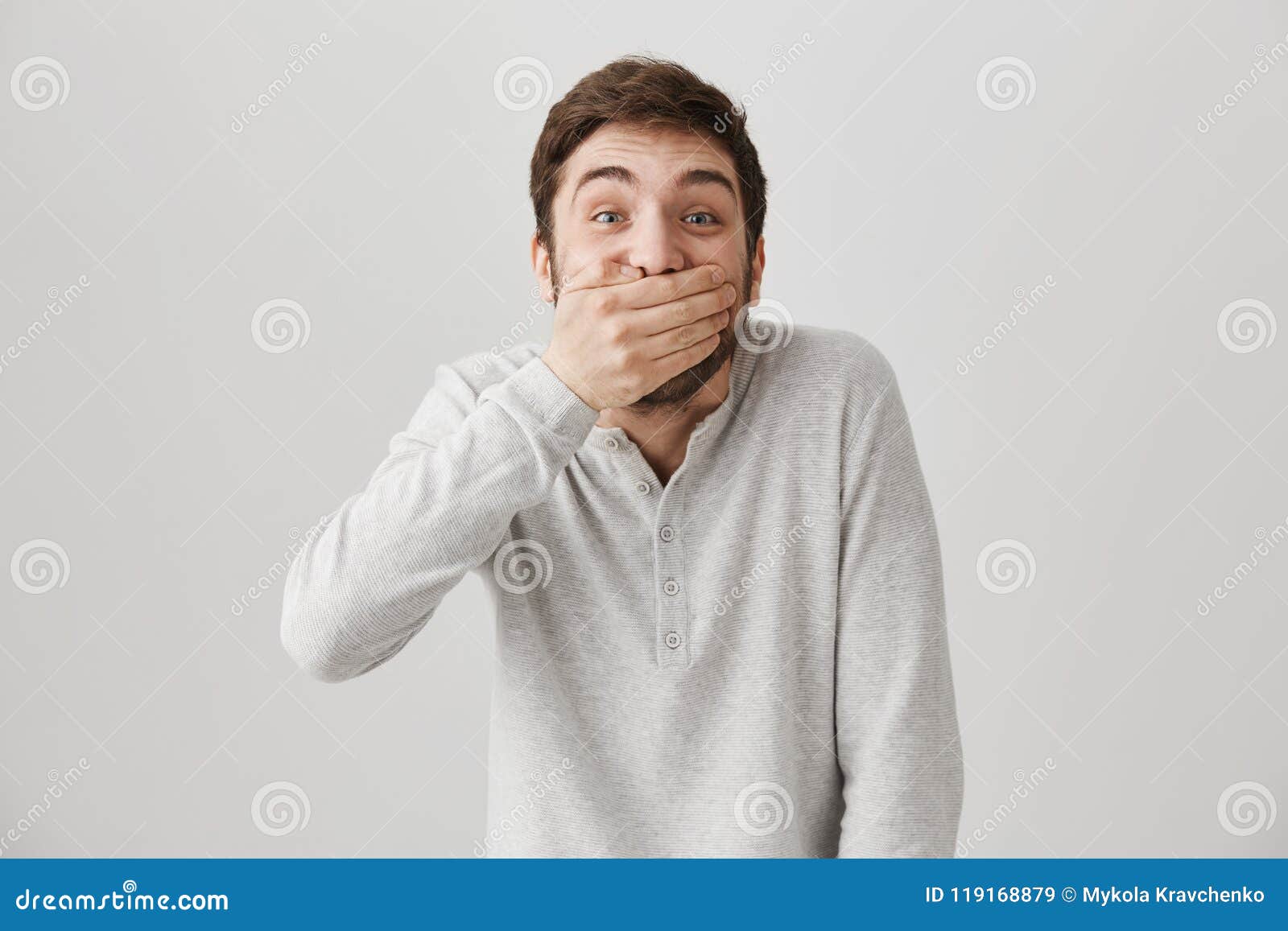 Emotive Positive Young Male Covering Mouth To Stop Laughter Or Hide