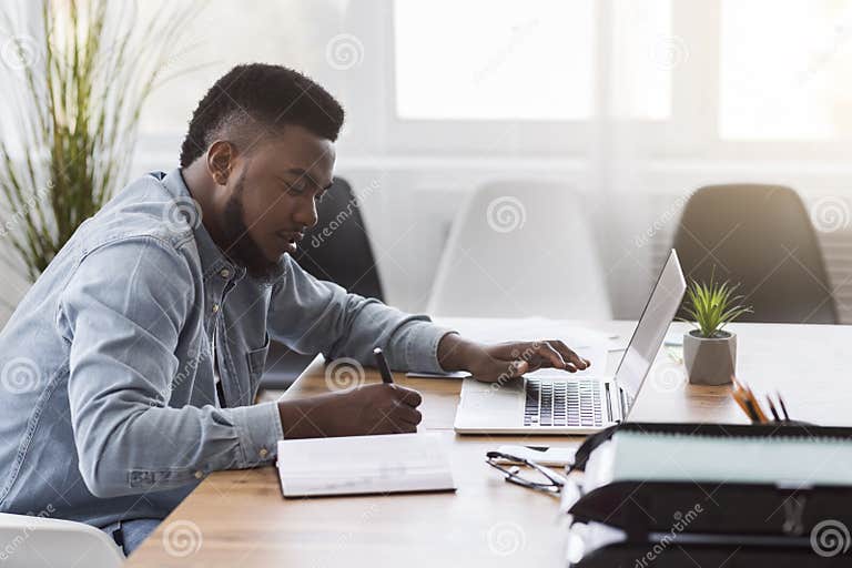 Employee Using Laptop and Taking Notes while Working in Office Stock ...