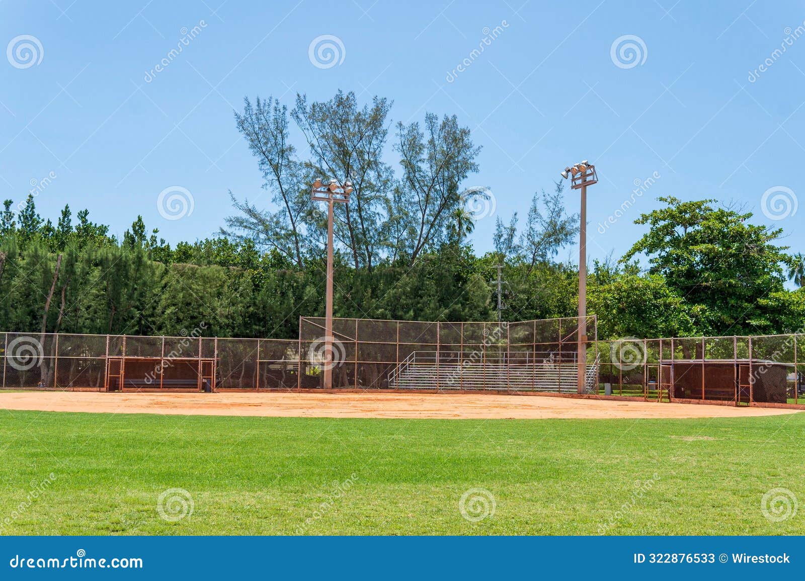 Empty Baseball Field with Green Grass, Benches, and Trees in the ...