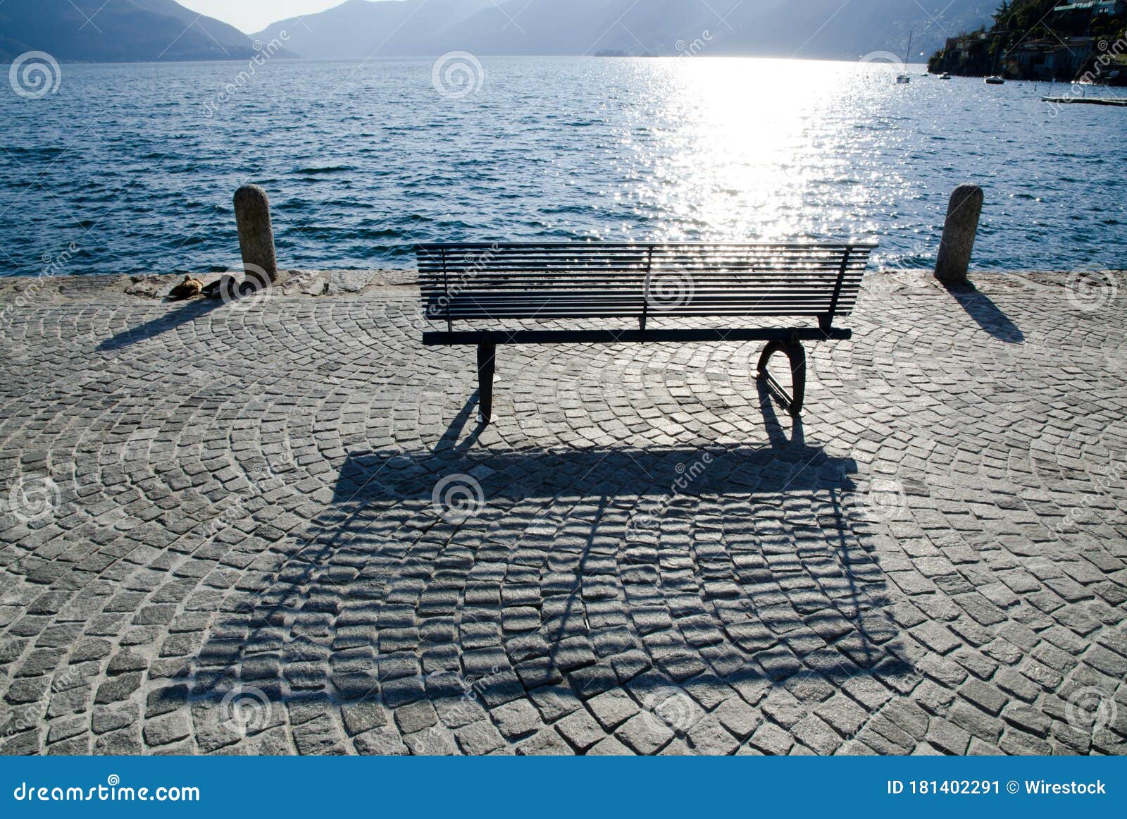 Empty Bench on the Body of the Lake with Shadows on the Cobblestone ...