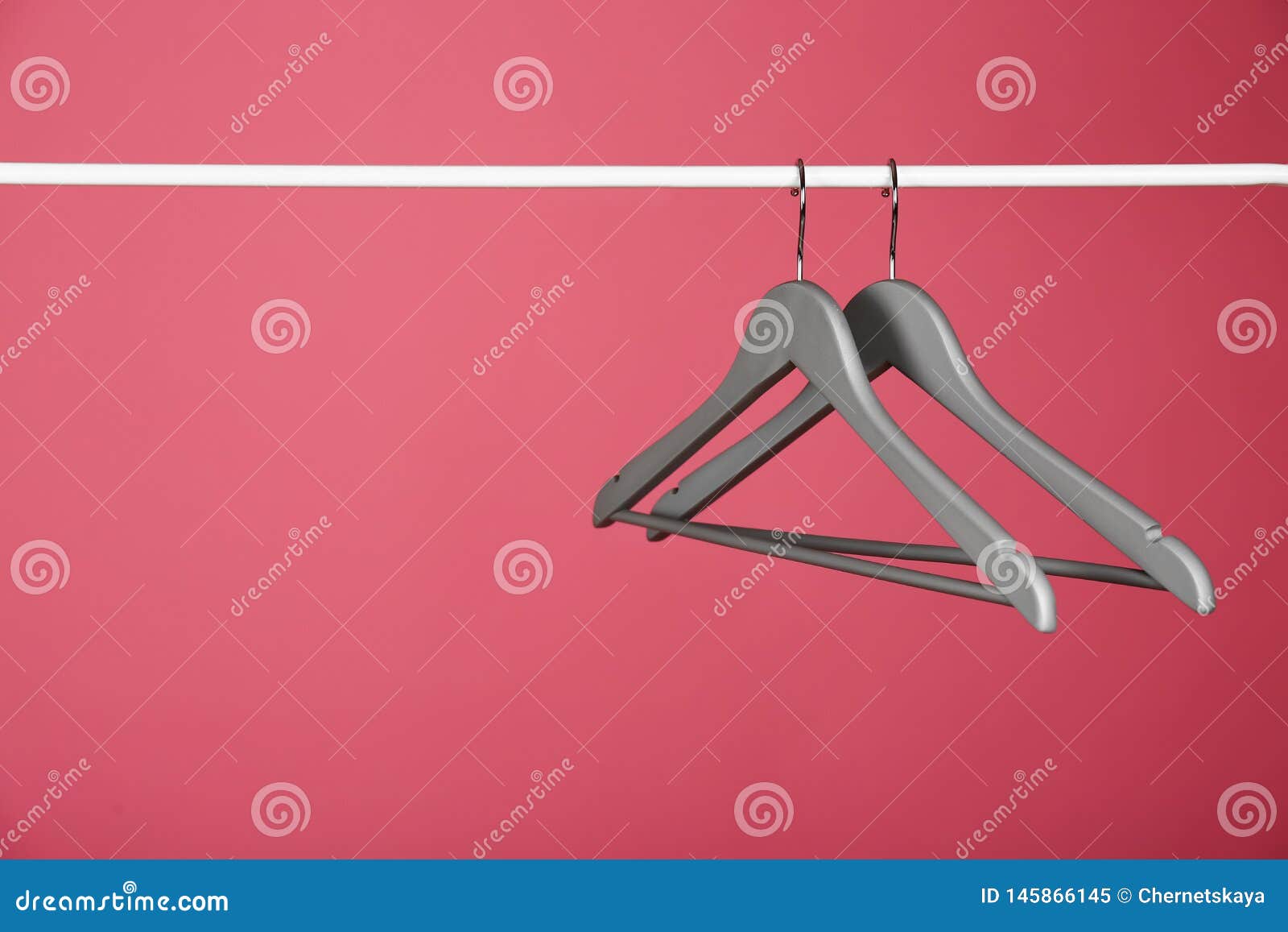 Empty Clothes Hangers on Metal Rail Against Color Background. Stock ...