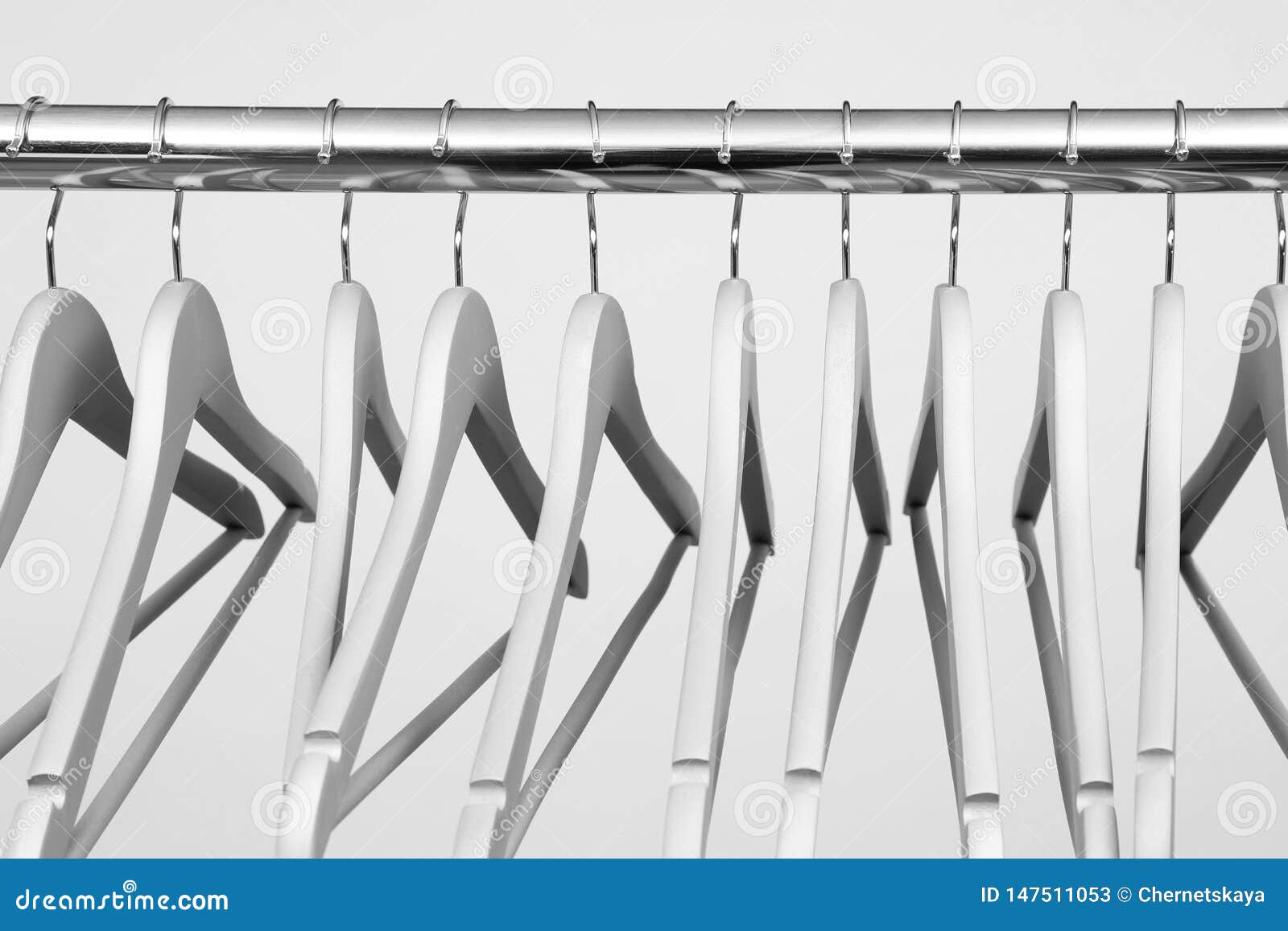 Empty Clothes Hangers on Metal Rail Against Light Background Stock ...