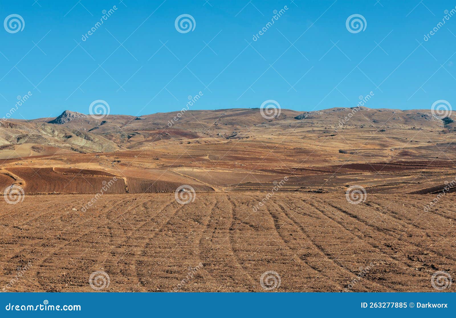 Empty Field in Front of Mountainous Terrain and the Blue Sky in a Sunny ...