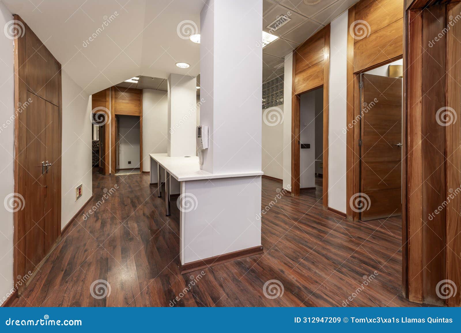 An Empty Office with a White Counter between Pillars, Built-in Cabinets ...