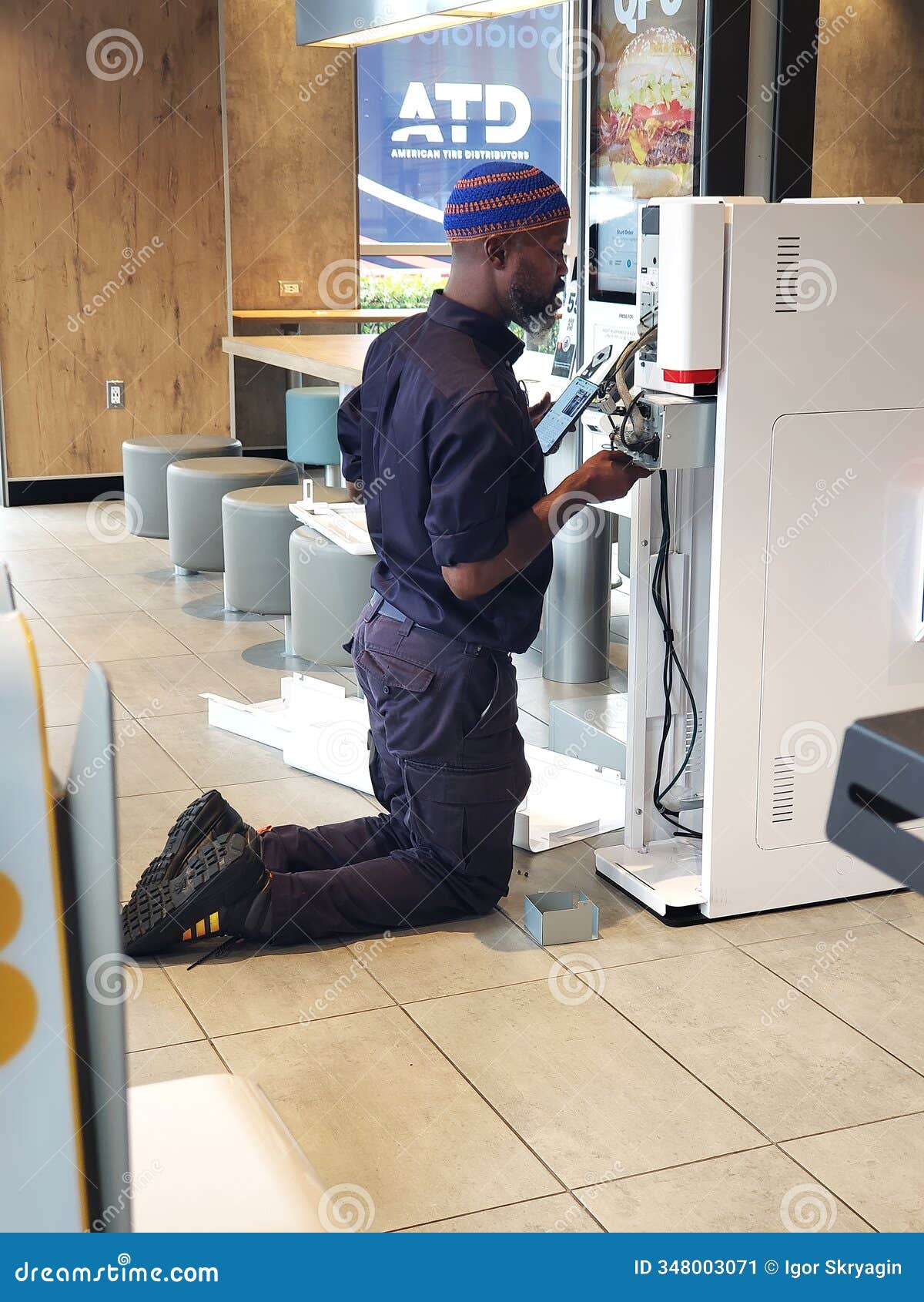 An Engineer Adjusts a New Customer Service Machine Using a Tablet at a ...