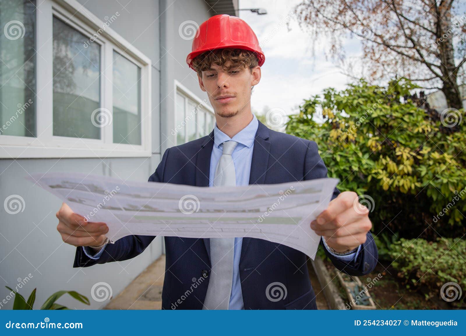 An Engineer Analyzes a Floor Plan while he is Wearing a Protective ...