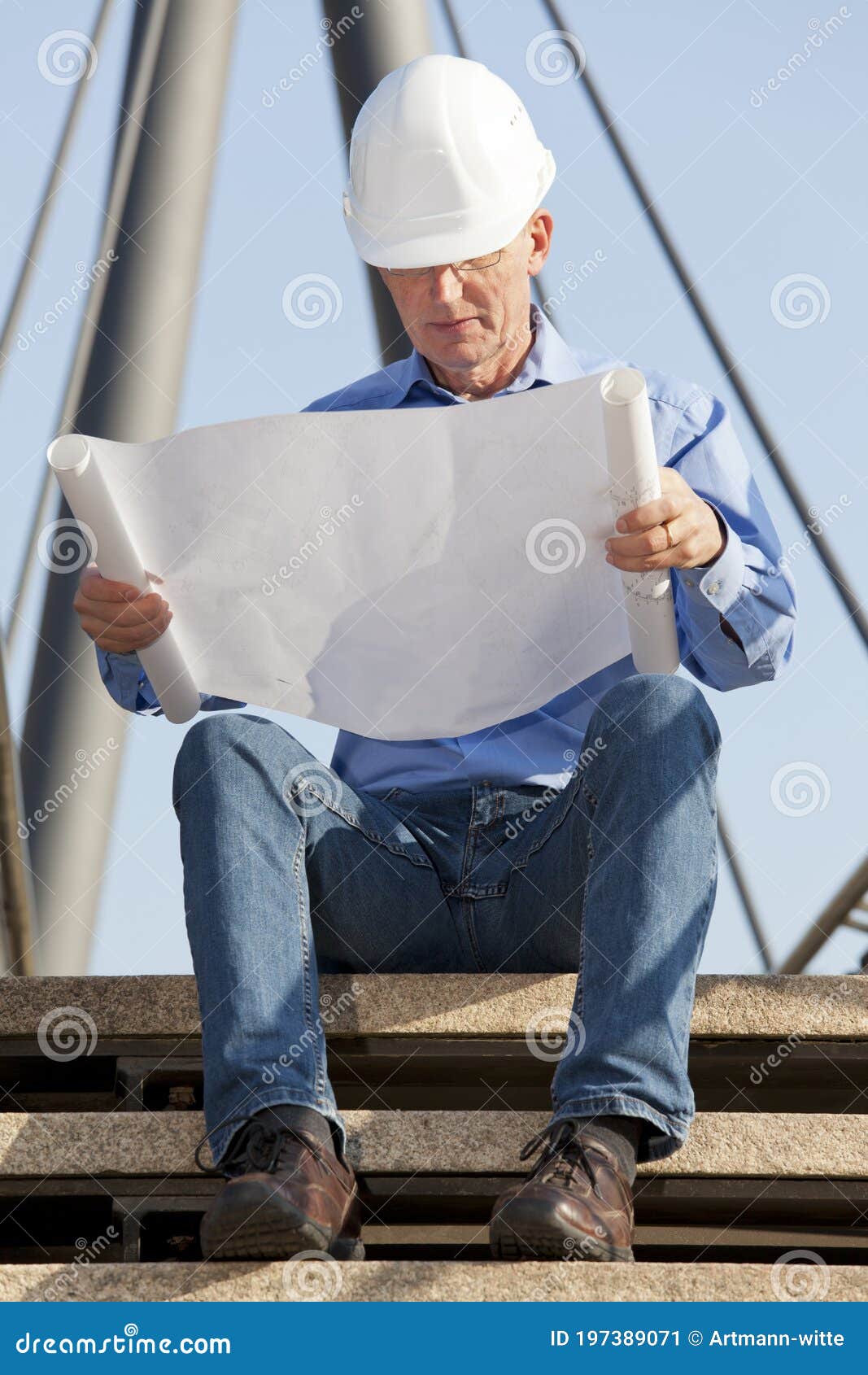 Engineer or Architect with Hard Hat Reading a Plan while Sitting in ...