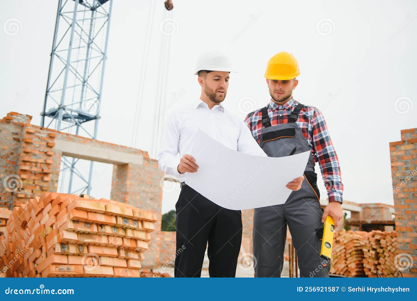 Engineer and Builder in Hard Hats Discussing Blueprint on Construction ...