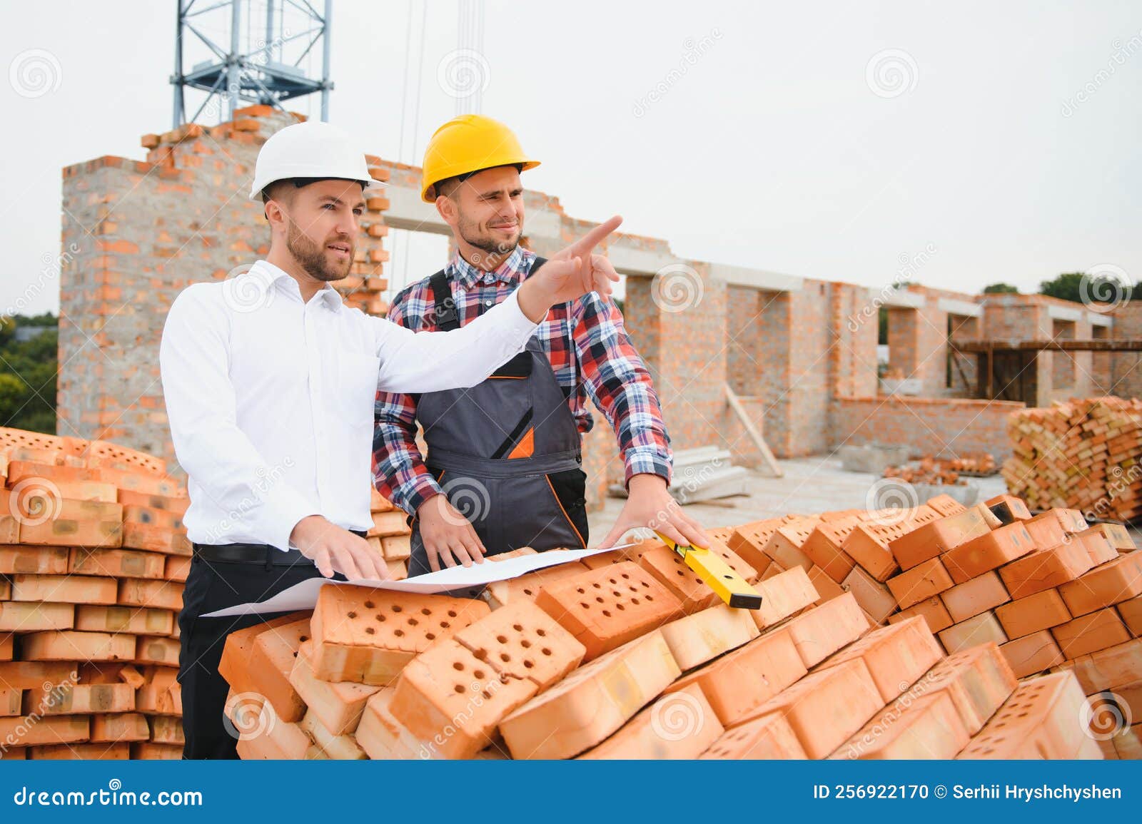 Engineer and Builder in Hard Hats Discussing Blueprint on Construction ...