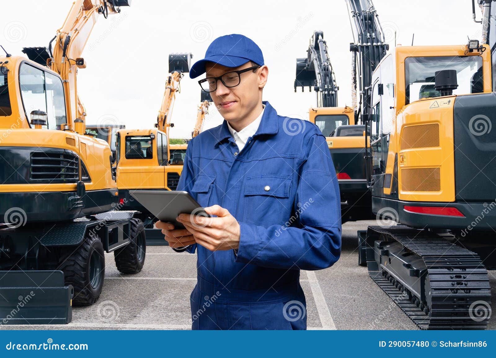 Engineer with a Digital Tablet Stands Next To Construction Excavators ...