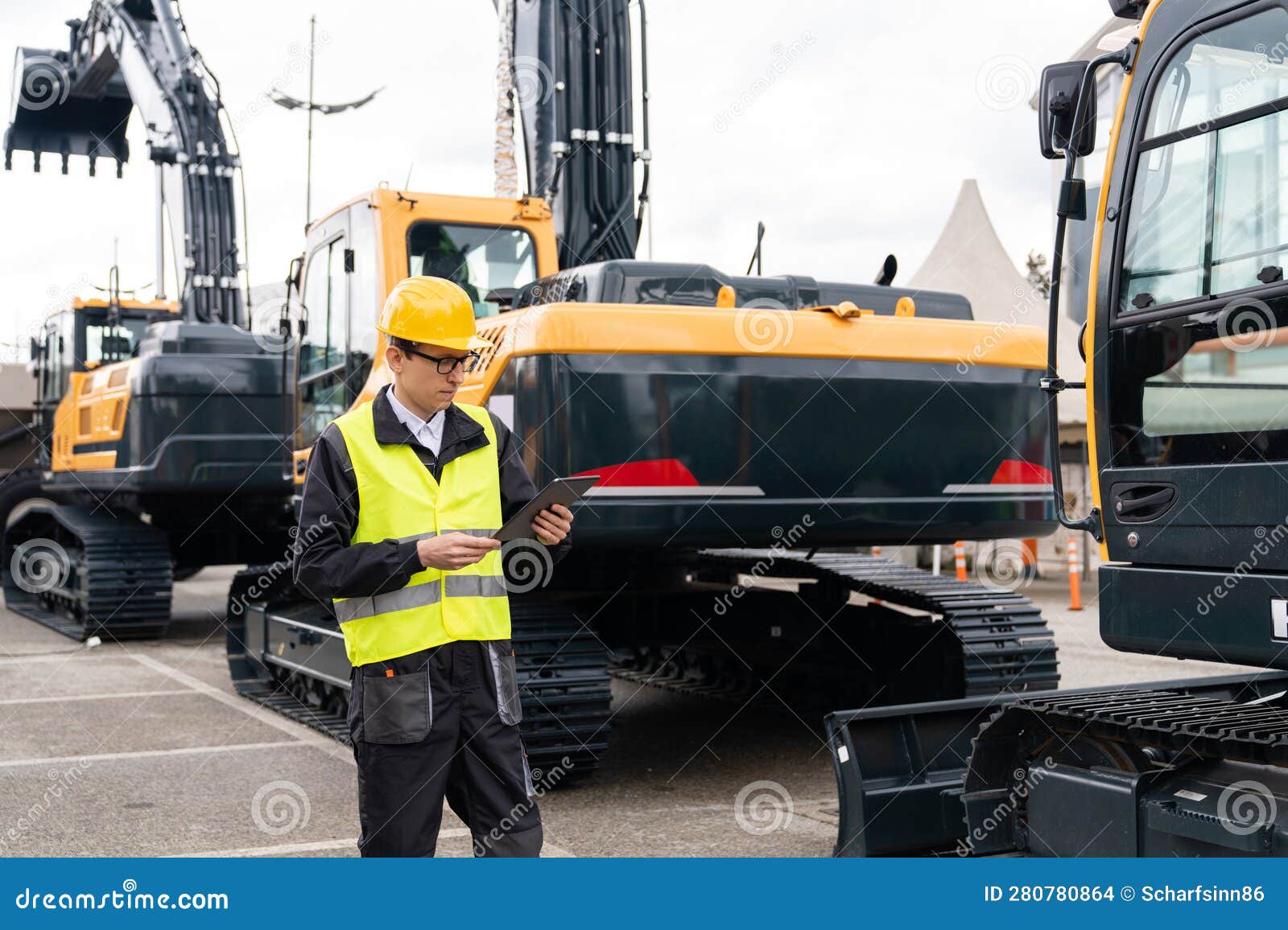Engineer with a Digital Tablet Stands Next To Construction Excavators ...
