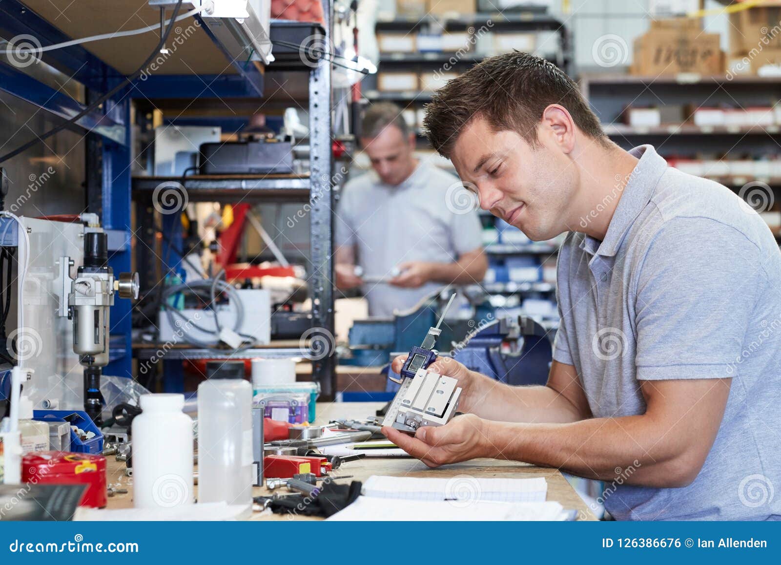 Engineer in Factory Measuring Component at Work Bench Using Micrometer ...