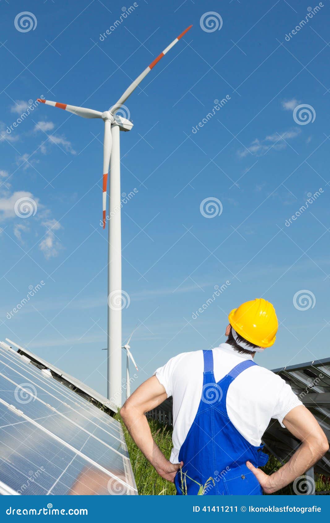 Engineer in Front of Solar Panels Looks at Wind Turbine Stock Image ...