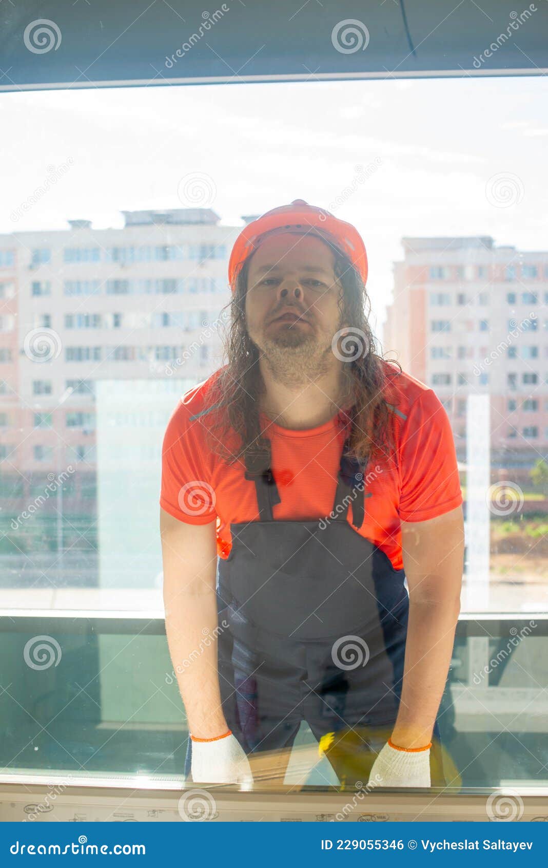 An Engineer in Gloves in a Helmet Makes a Face Behind the Glass Stock ...
