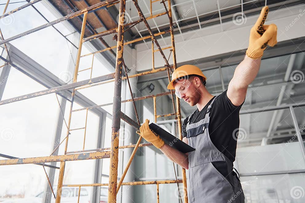 Engineer in Grey Uniform with Notepad in Hands Works Indoors in Modern ...