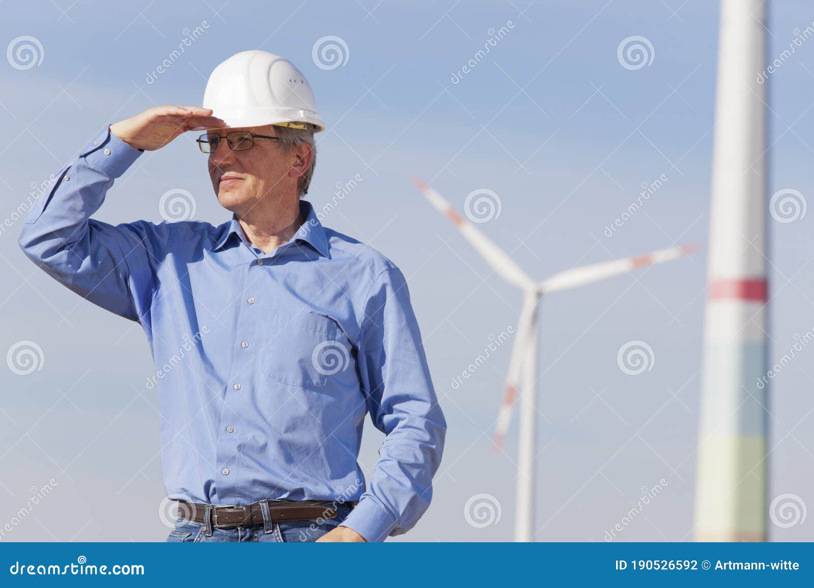Engineer with Hard Hat in Front of a Windfarm Looking for a Bright ...