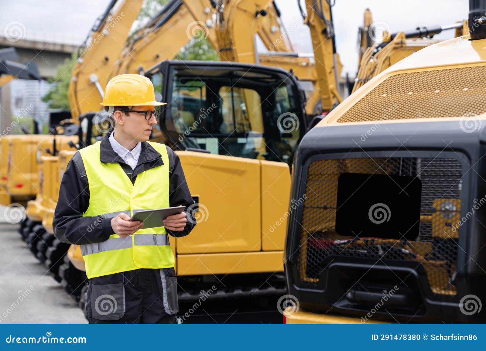Engineer in a Helmet with a Digital Tablet Stands Next To Construction ...