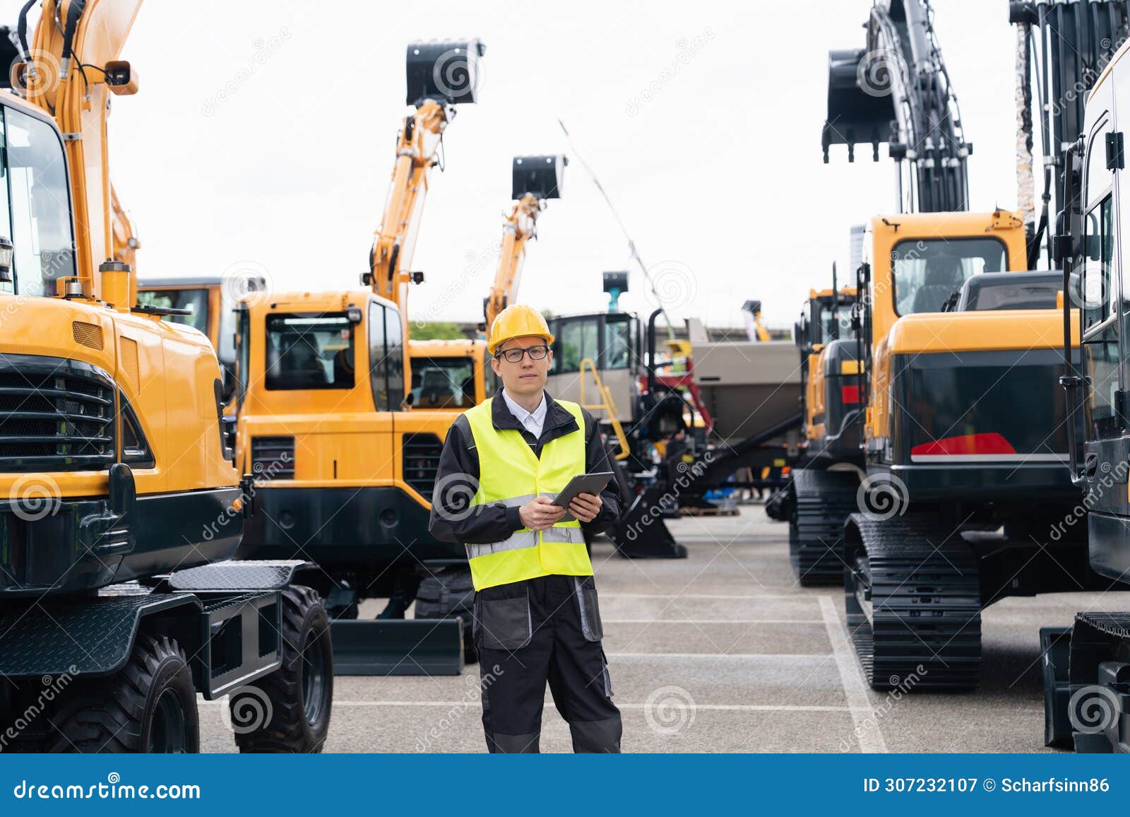 Engineer in a Helmet with a Digital Tablet Stands Next To Construction ...