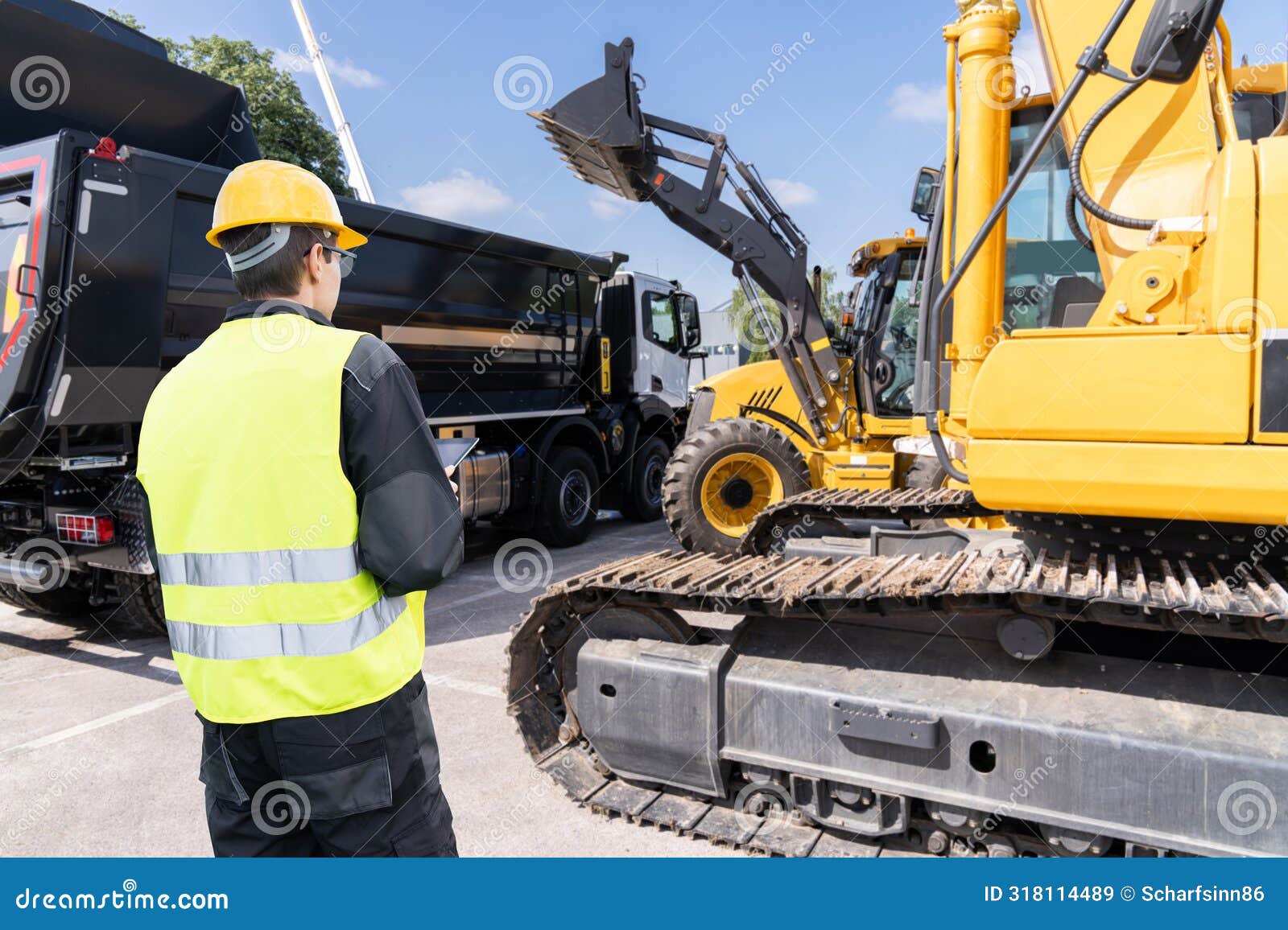 Engineer in a Helmet with a Digital Tablet Stands Next To Construction ...