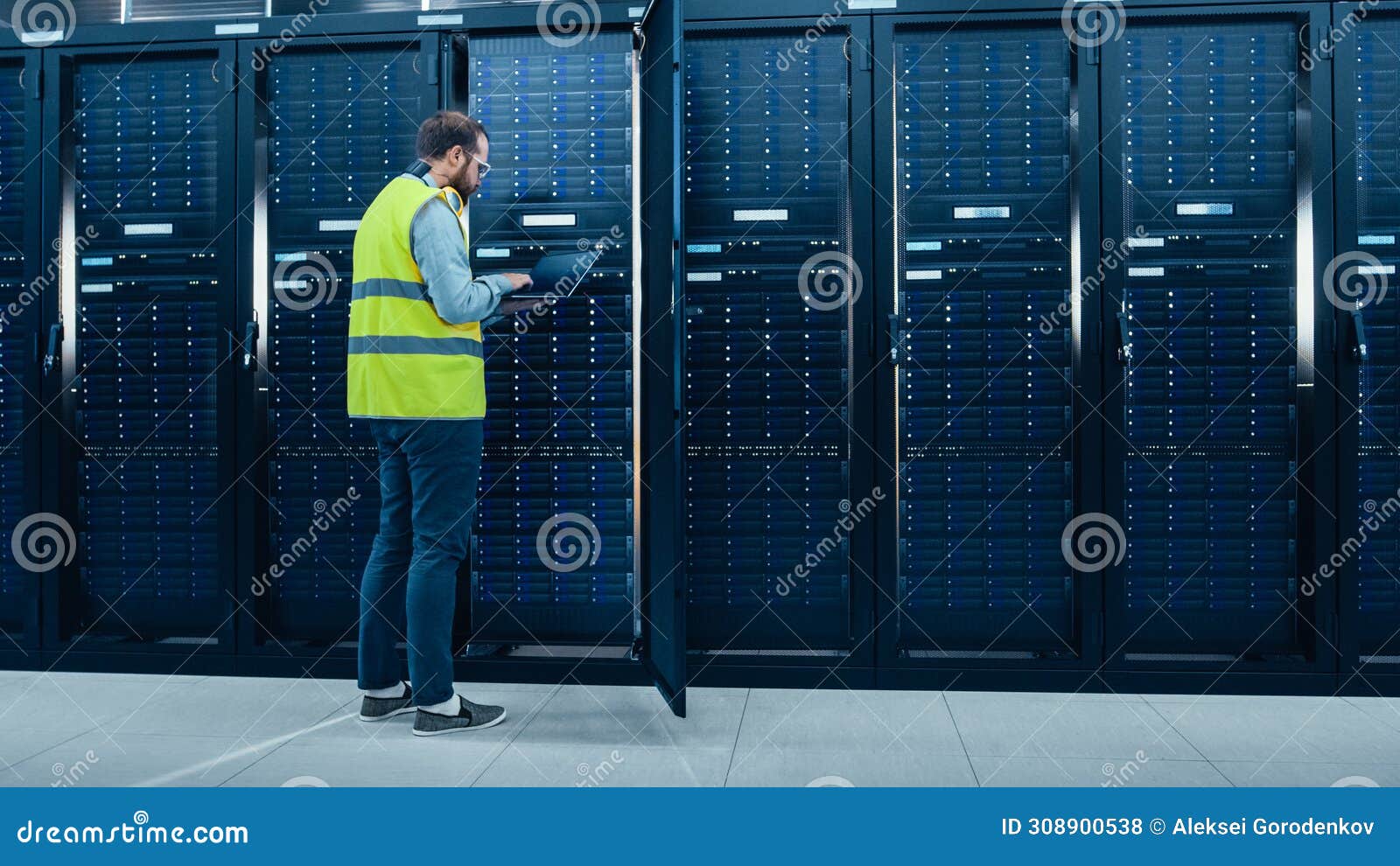 It Engineer in High Visibility Vest is Working on Laptop in Data Center ...