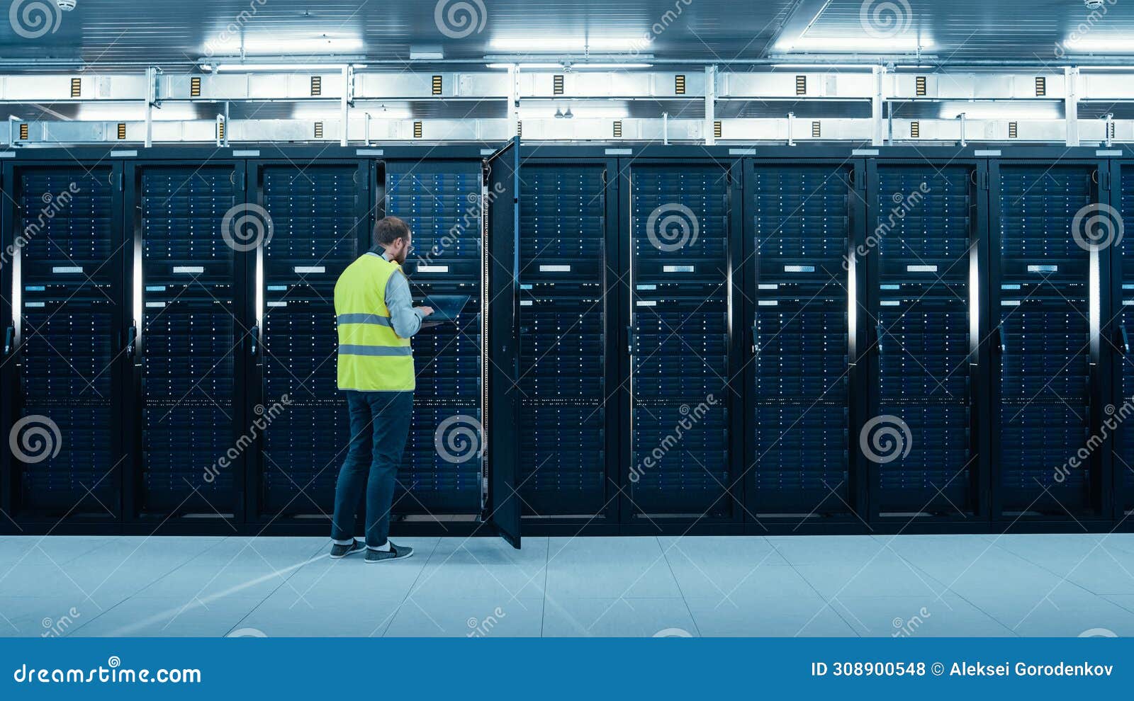 It Engineer in High Visibility Vest is Working on Laptop in Data Center ...