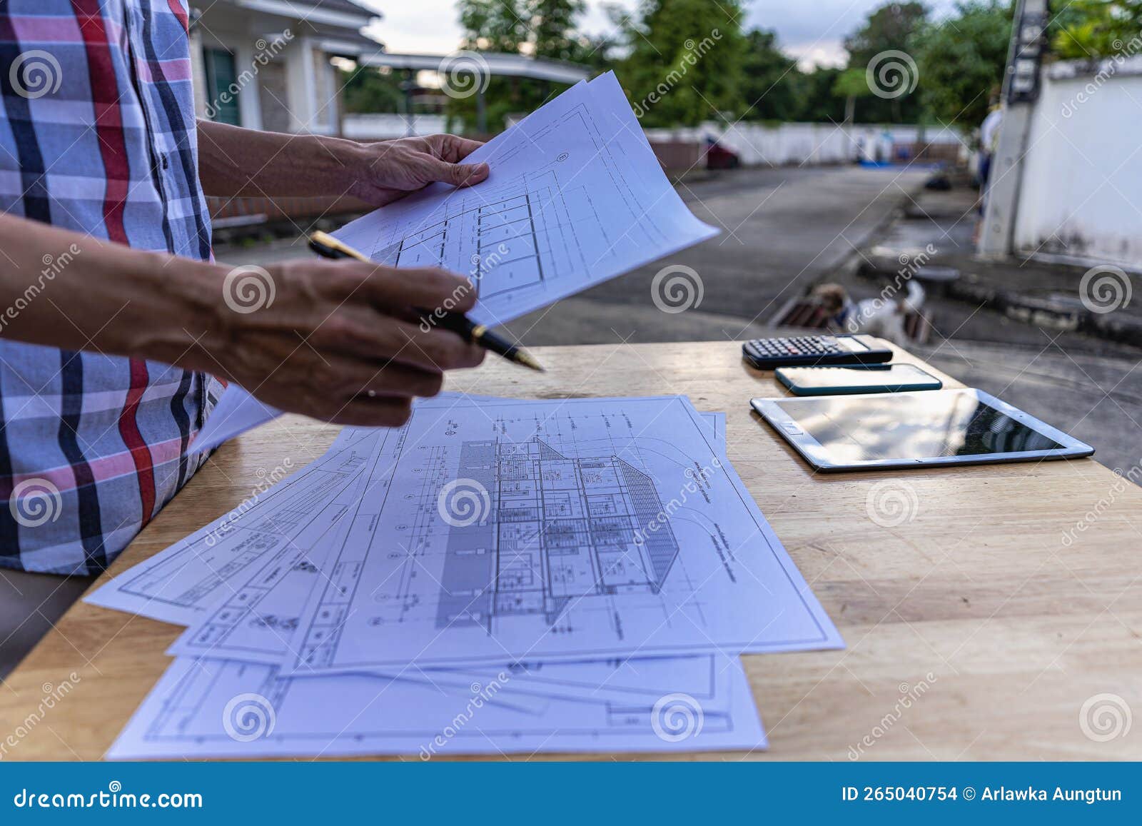 Engineer Pointing at Blueprint and Using Laptop To Draw Building Design ...