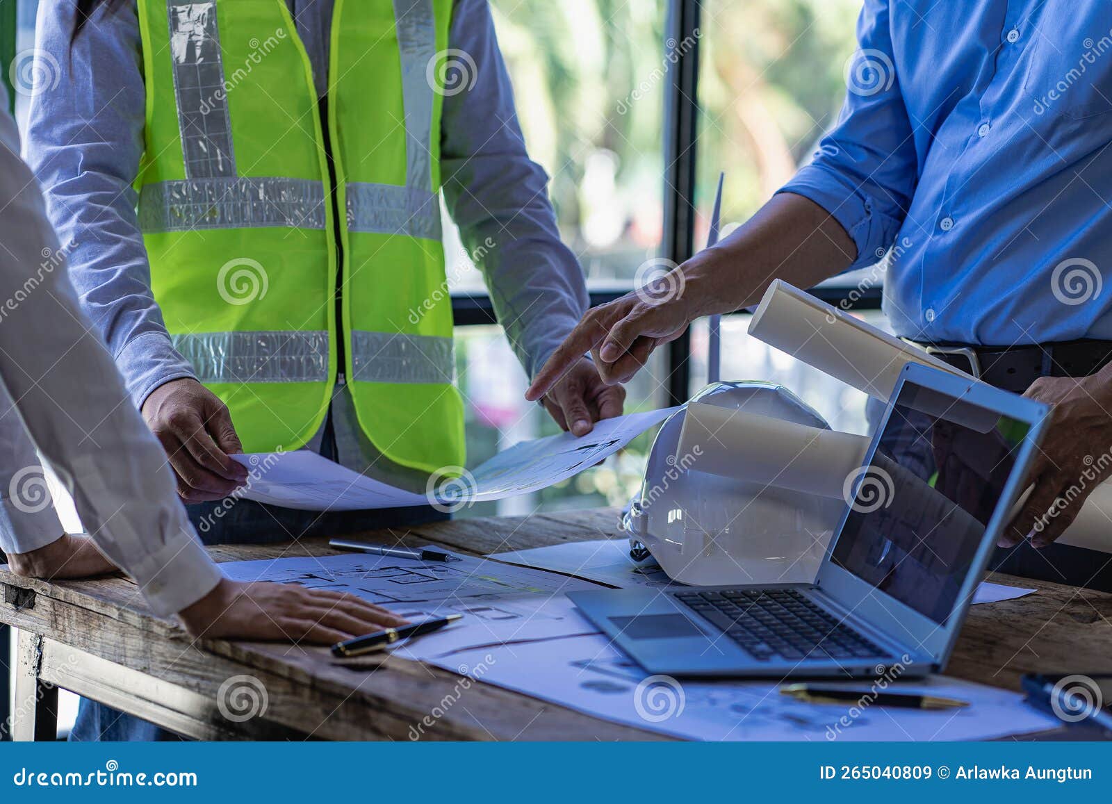 Engineer Pointing at Blueprint and Using Laptop To Draw Building Design ...