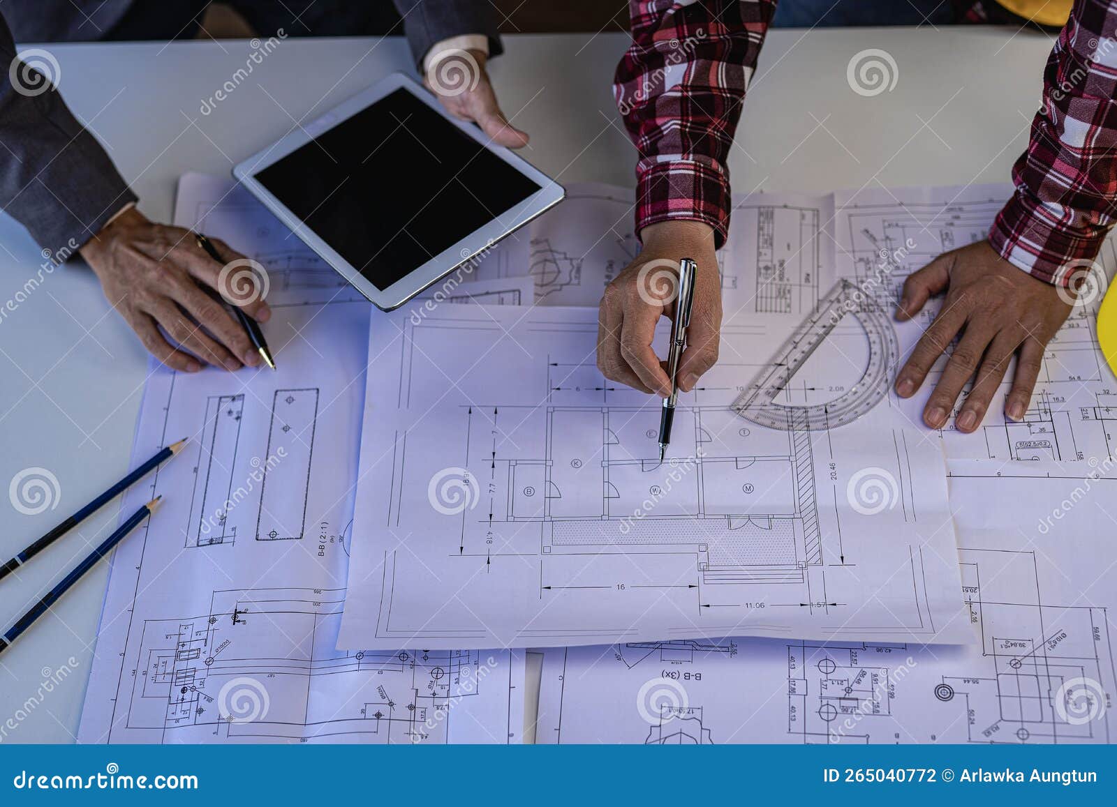 Engineer Pointing at Blueprint and Using Laptop To Draw Building Design ...