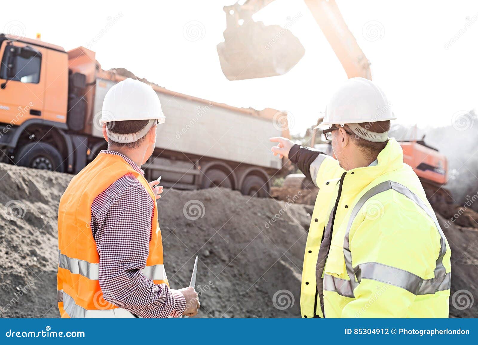 Engineer Pointing at Vehicles while Discussing at Construction Site ...