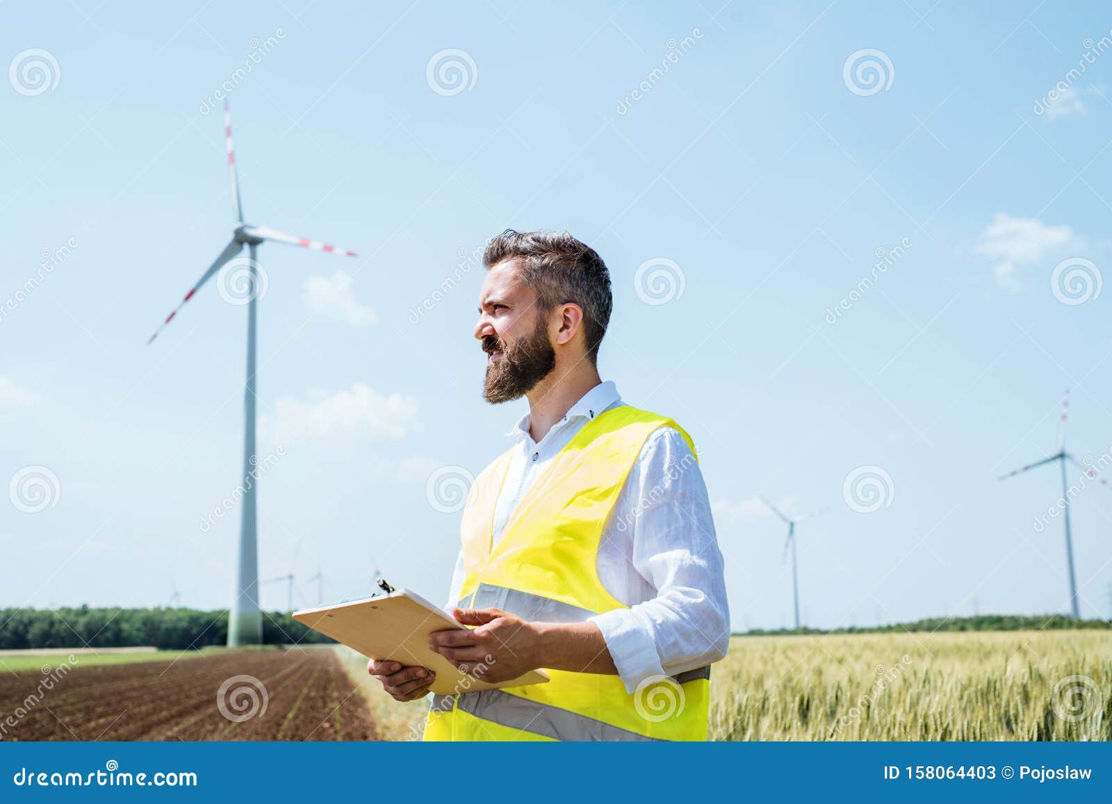 An Engineer Standing on a Field on Wind Farm, Making Notes. Stock Image ...