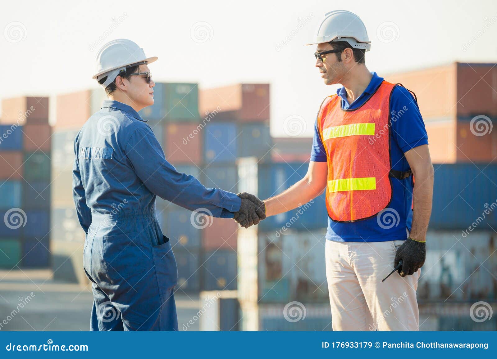 Engineer and Worker Handshake with Blurred Containers Cargo Background ...