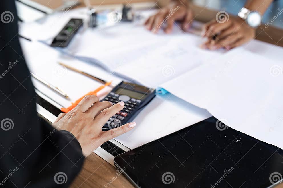 Engineer Working on Blueprints and Calculations with Calculator and Technical Tools on Desk ...
