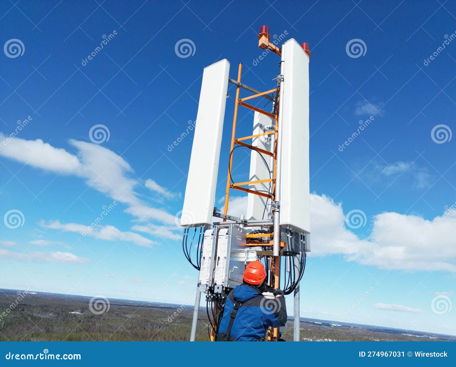 Engineer Working on a Telecommunications Tower Against the Background ...