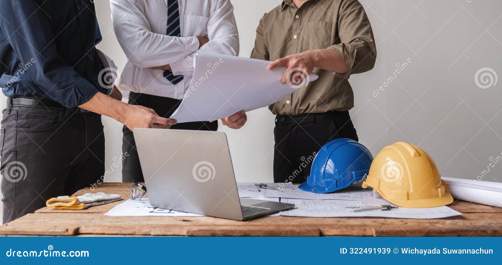 Engineering Team Collaborating on Work Plans at Table with Blueprints ...