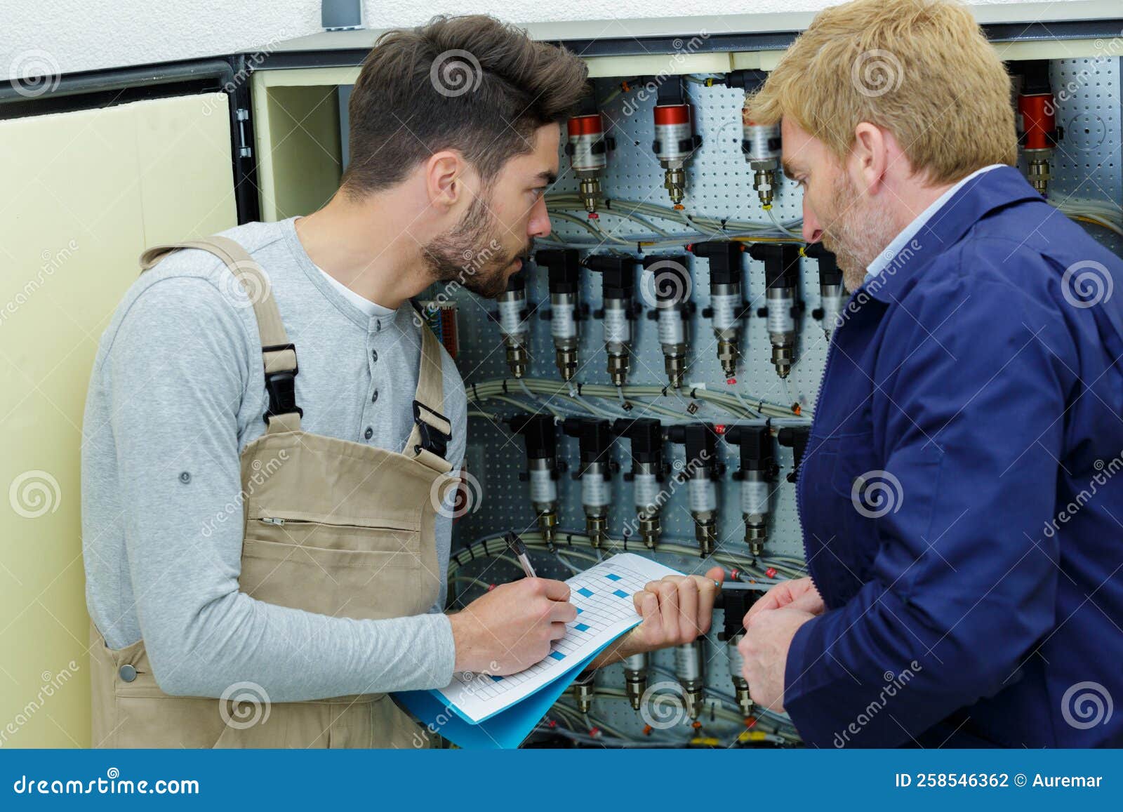 Engineers with Clipboard Checking Equipment in Cabinet Stock Photo ...