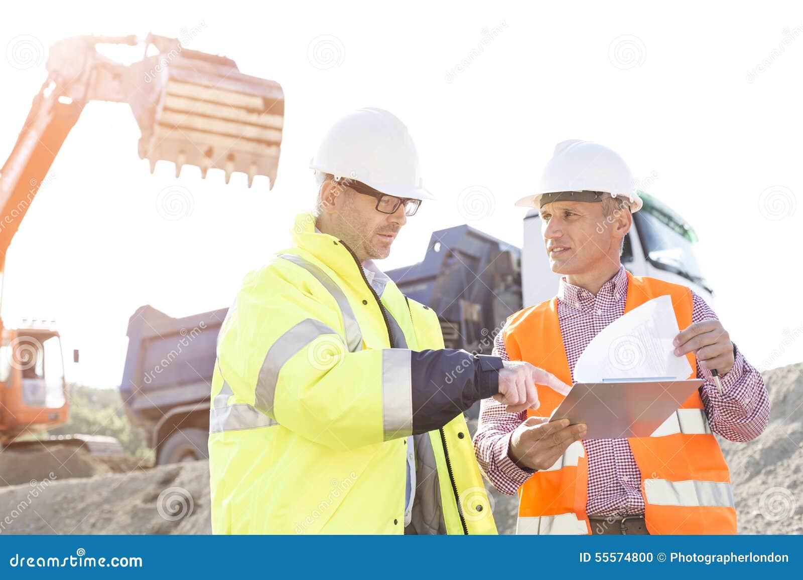 Engineers Discussing Over Documents at Construction Site Stock Photo ... Engineers Discussing Over Documents at Construction Site Stock Photo ...