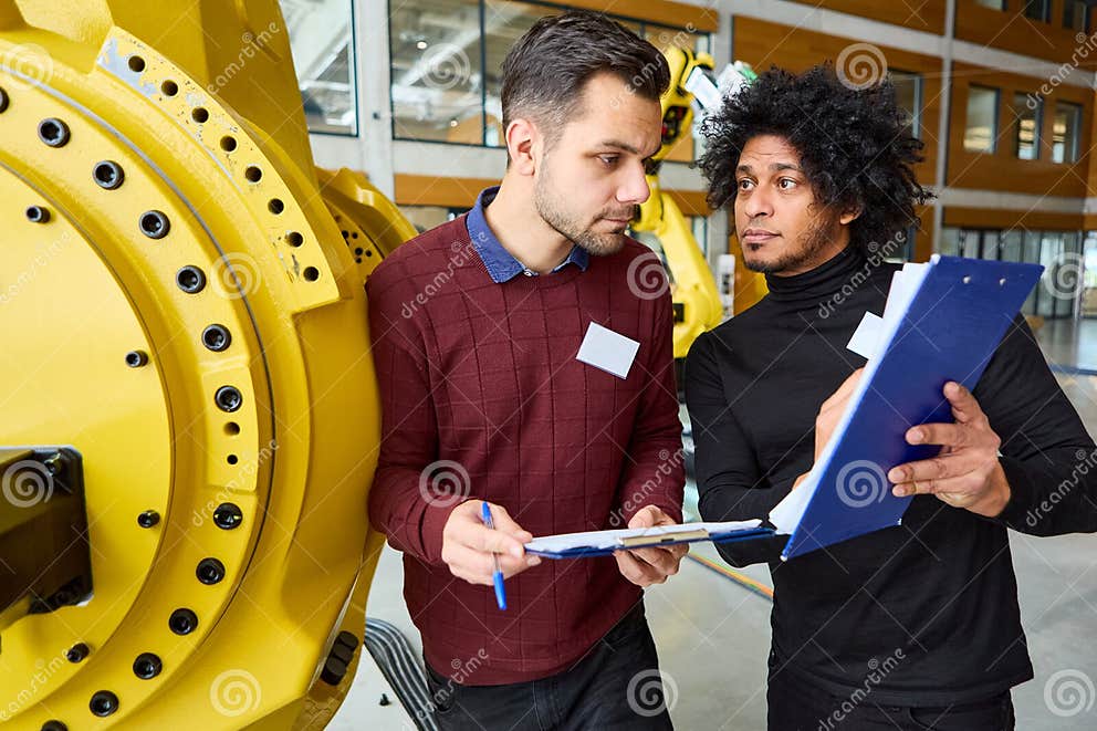 Engineers Discussing Robotics Programming and Automation with a Yellow Industrial Robot Stock ...