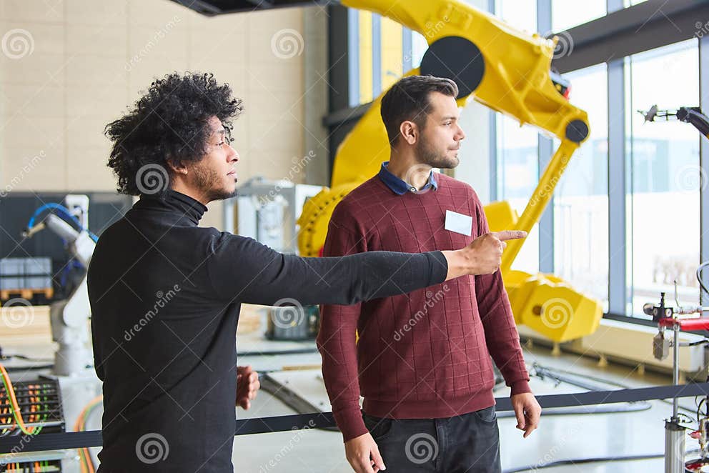 Engineers Discussing Robotics Technology and Programming in an Industrial Setting with Advanced ...