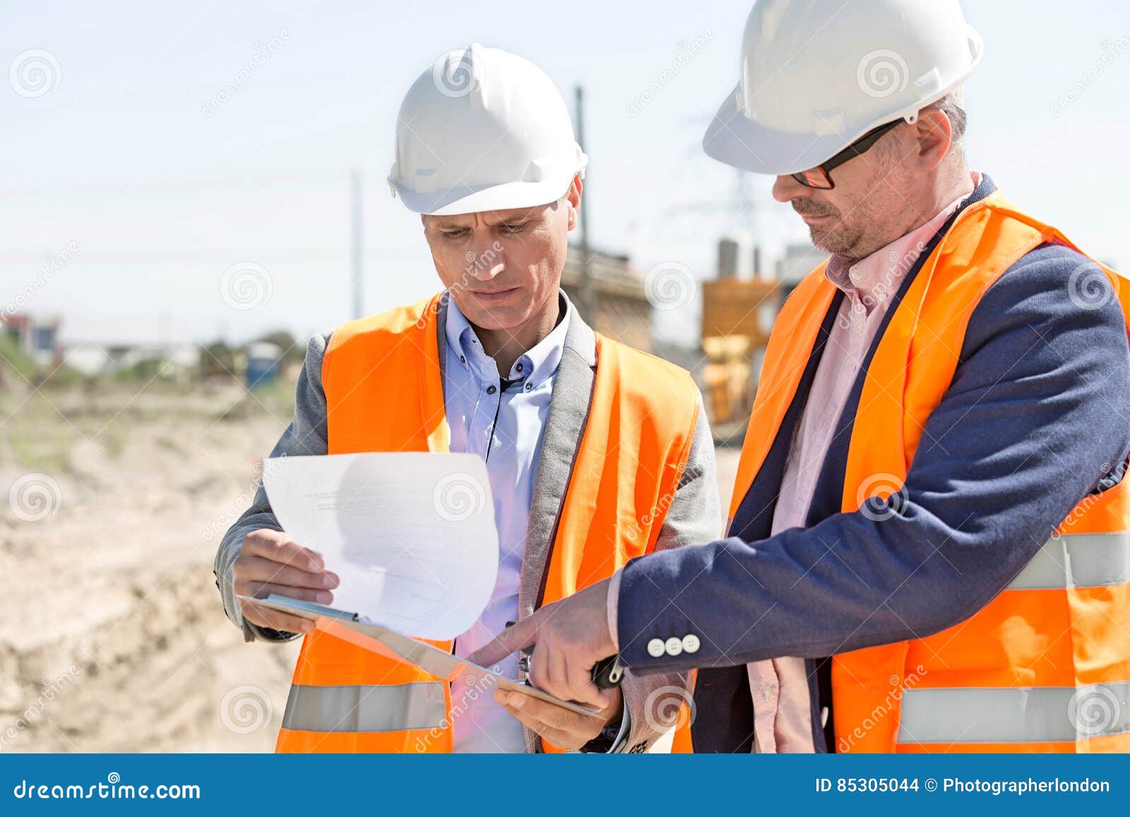Engineers Examining Documents on Clipboard at Construction Site Against ...