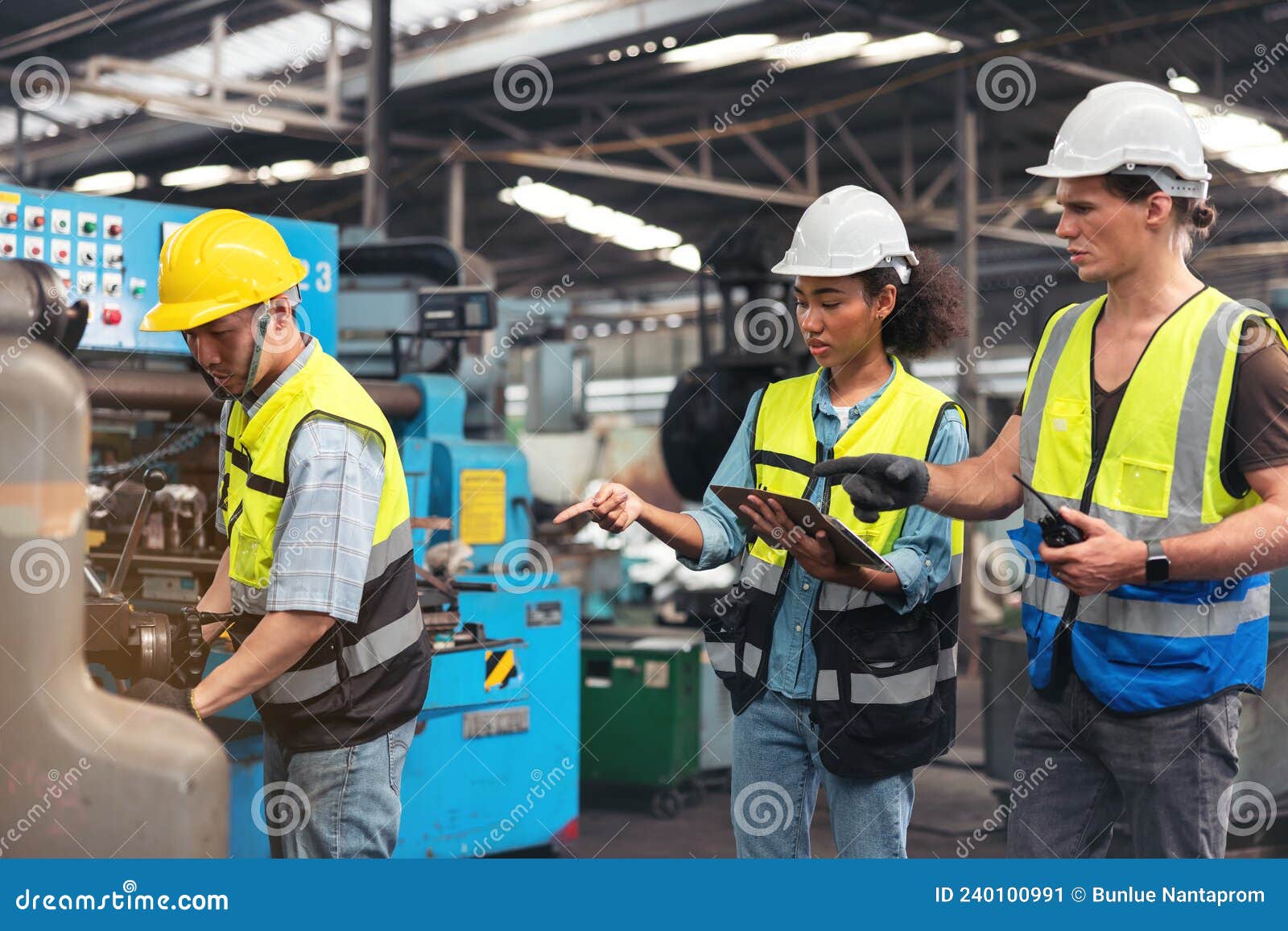Engineers in an Industry Plant Setting Up Machines Vs a Background of a ...