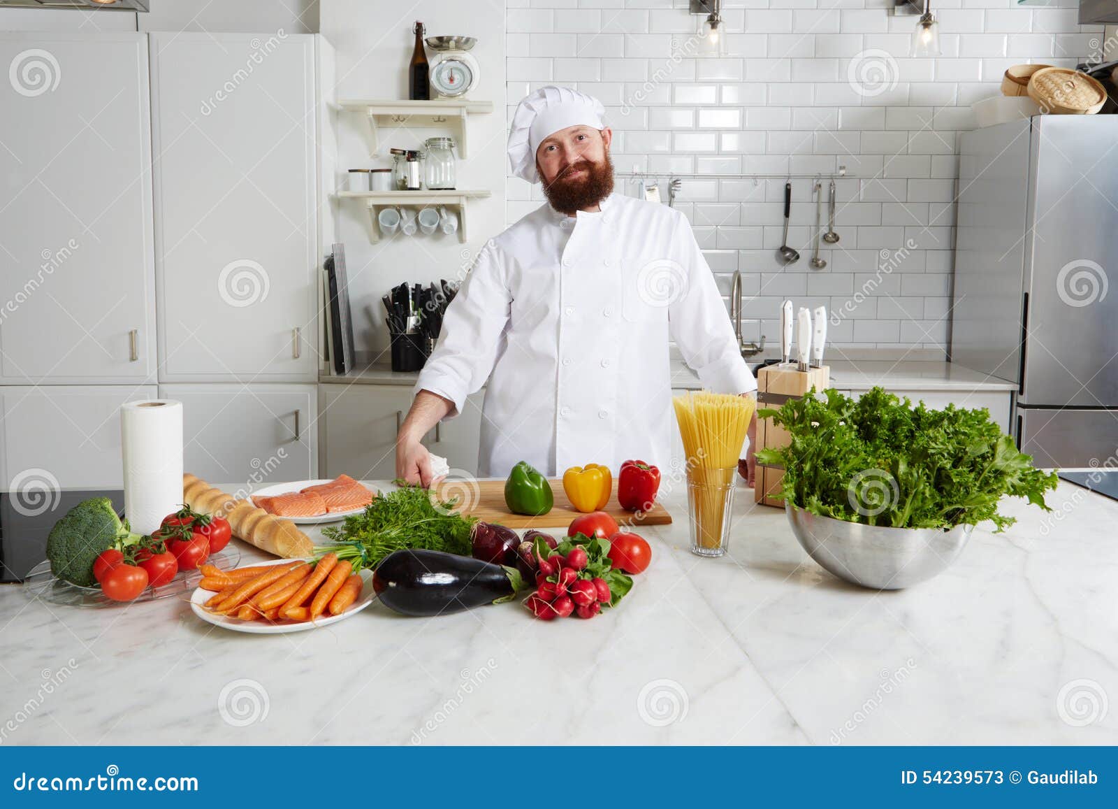 Enjoyable Smiling Chef with Fresh Vegetables on Big Table Standing in ...