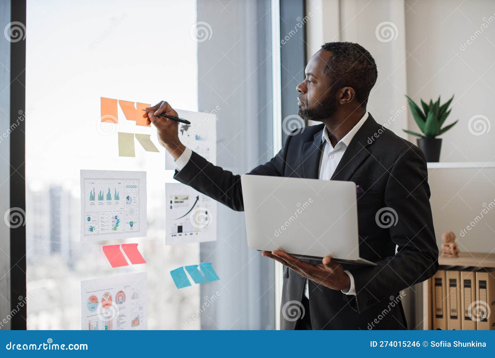 Entrepreneur Noting Down Details Using Laptop and Graphs Stock Photo ...