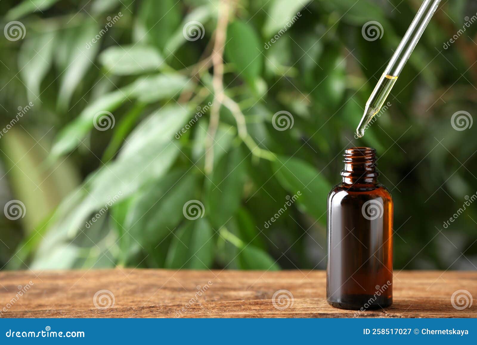 Essential Oil Dripping from Pipette into Bottle on Wooden Table, Space ...