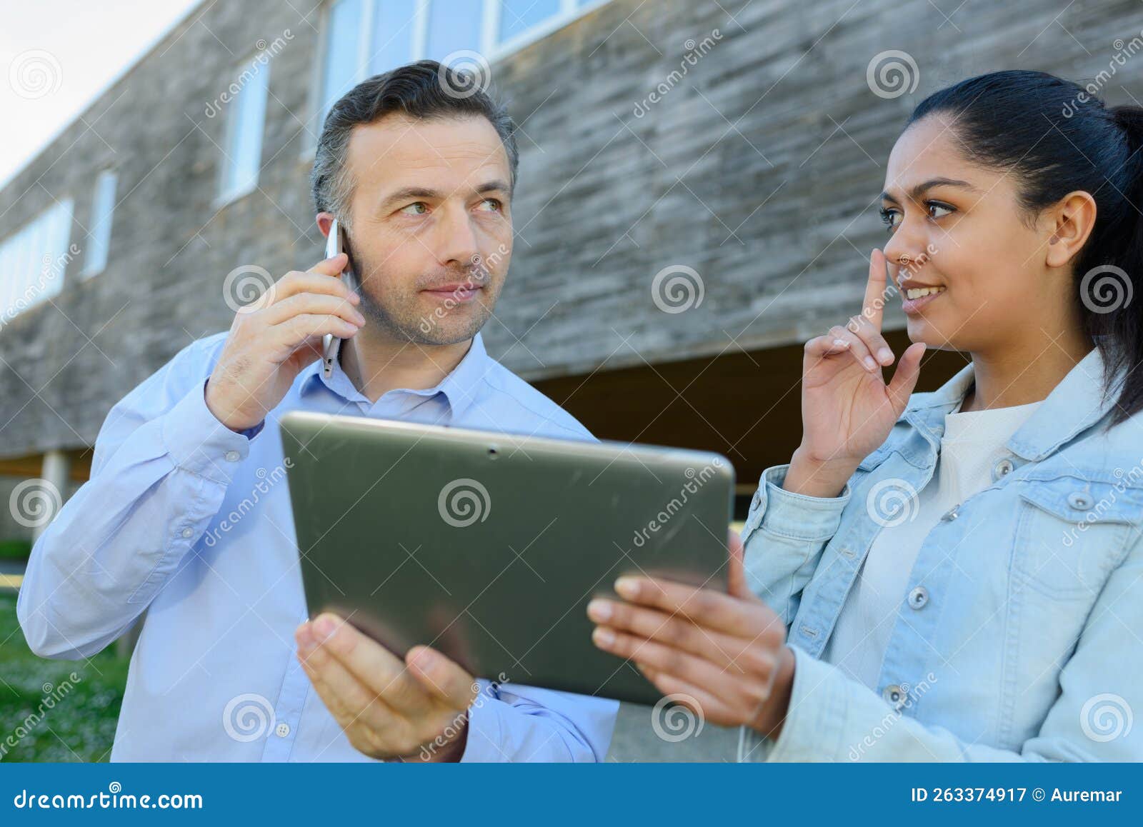 Estate Agent with Client Using Tablet and Smartphone Outside Property ...